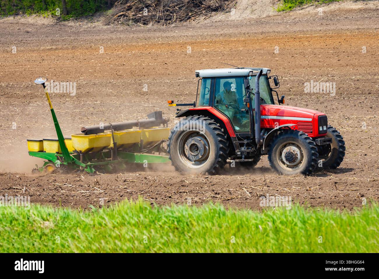 Tractor working across a wide farm field, fertilizing soil and planting ...