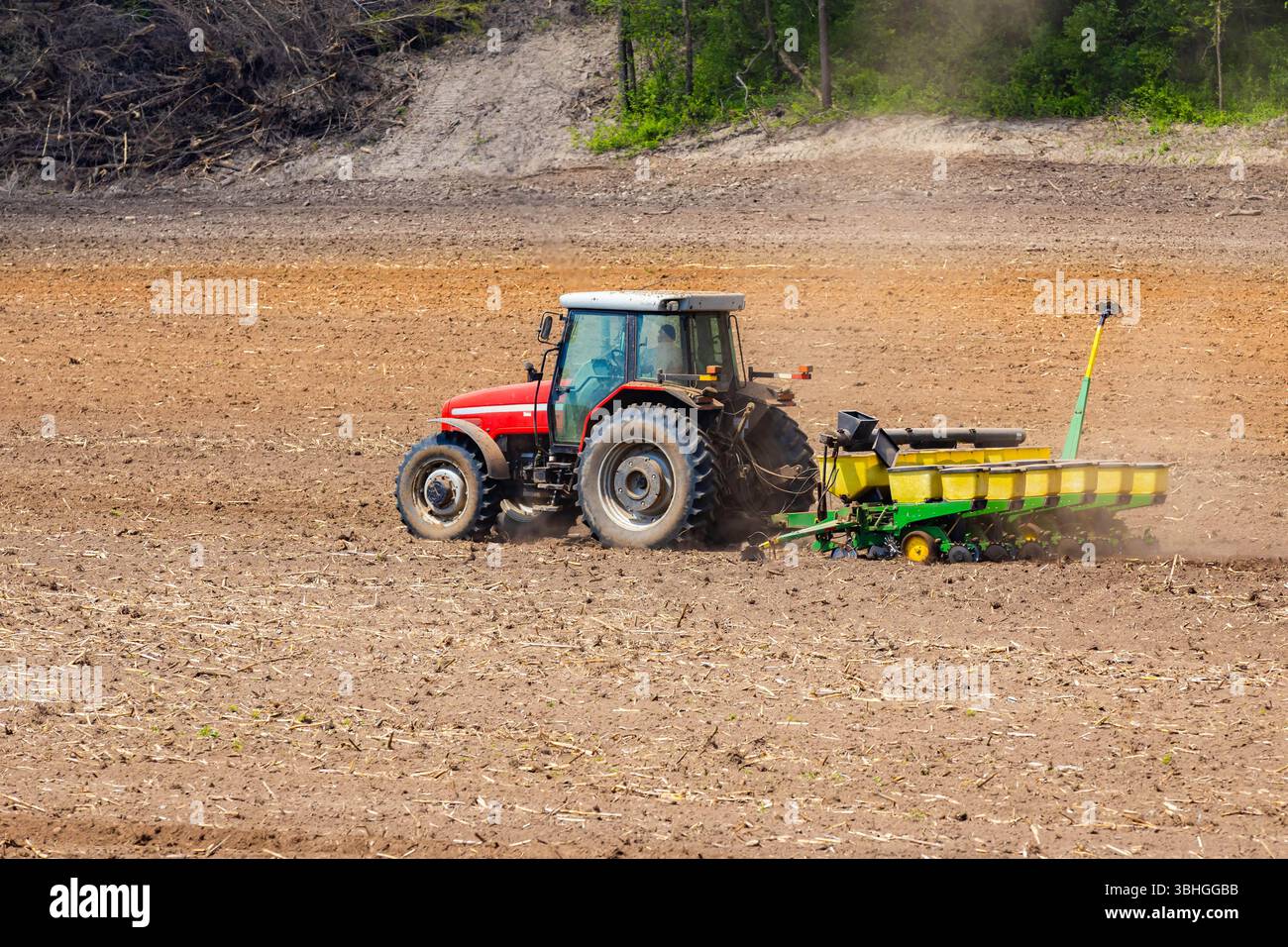 Tractor working across a wide farm field, fertilizing soil and planting ...