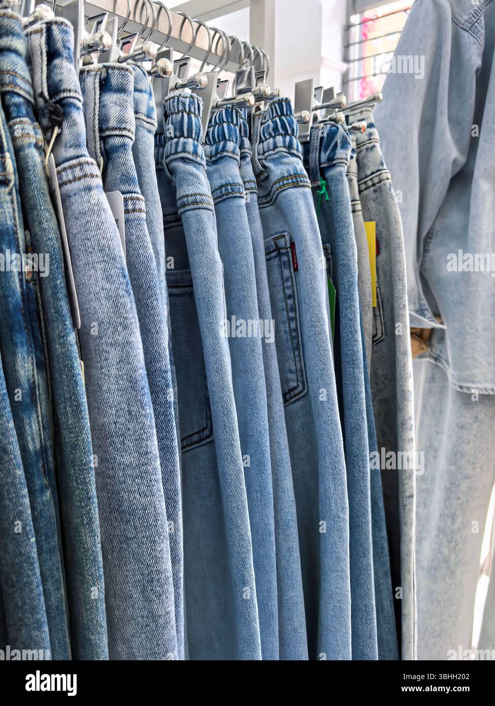 Rows of assorted denim jeans hanging neatly on a rack in a clothing ...
