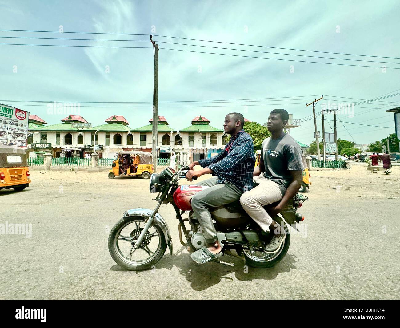 Urban street scene in an African city showing a motorcycle taxi (okada ...