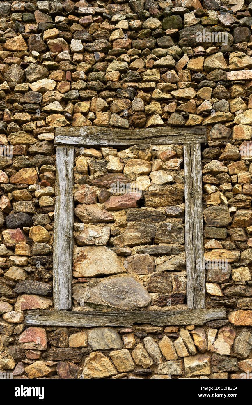 A wall constructed of unevenly arranged stones features a striking ...