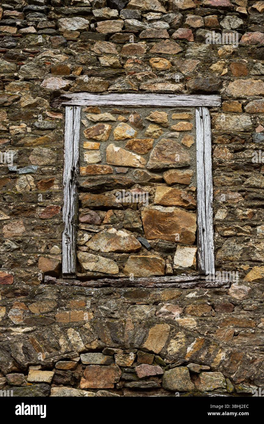 A wall constructed of unevenly arranged stones features a striking ...