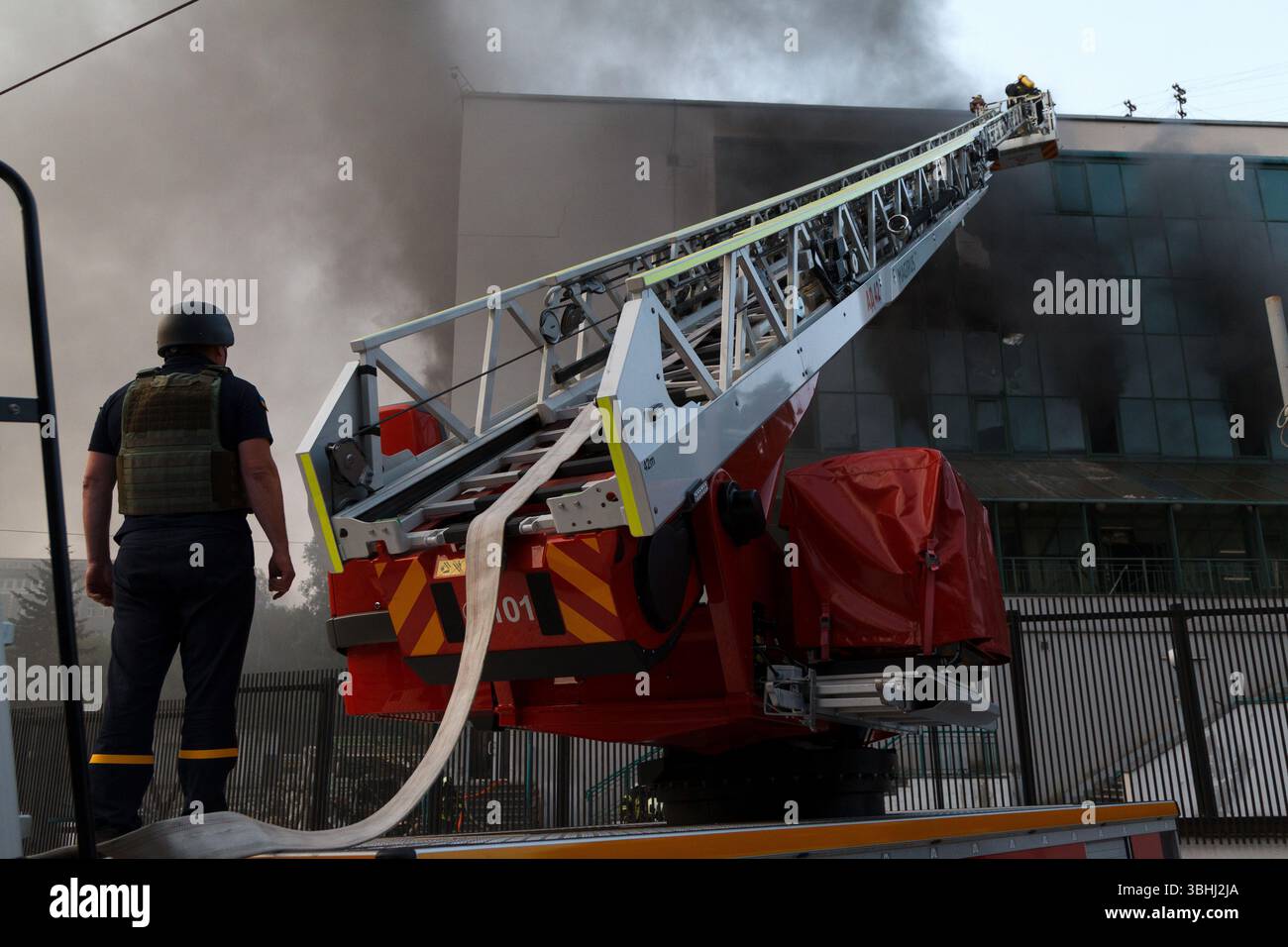 Firefighters use a turntable ladder to suppress a fire in an office ...