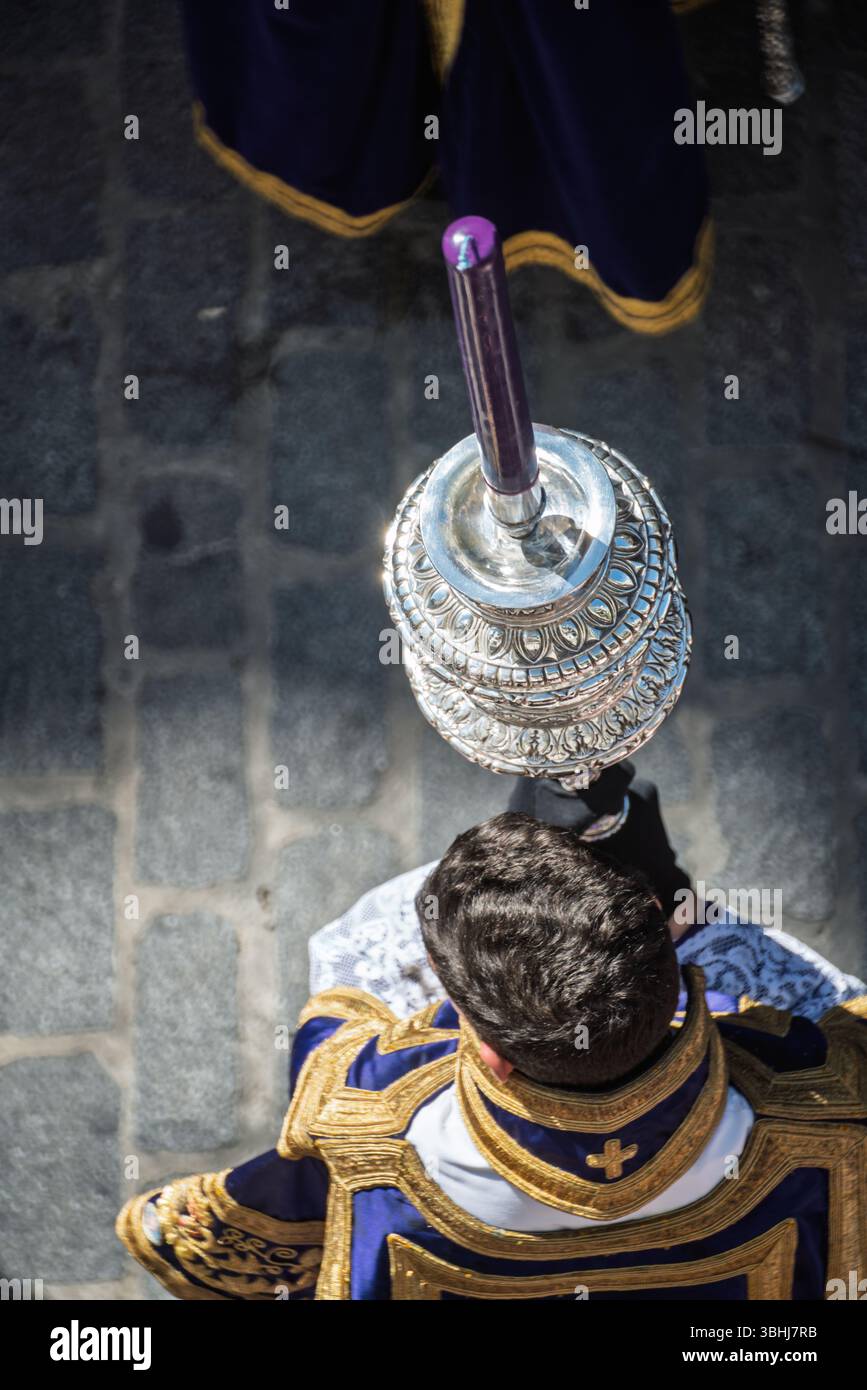 An acolyte walks through the streets of Seville, carrying a decorated processional candle during ...