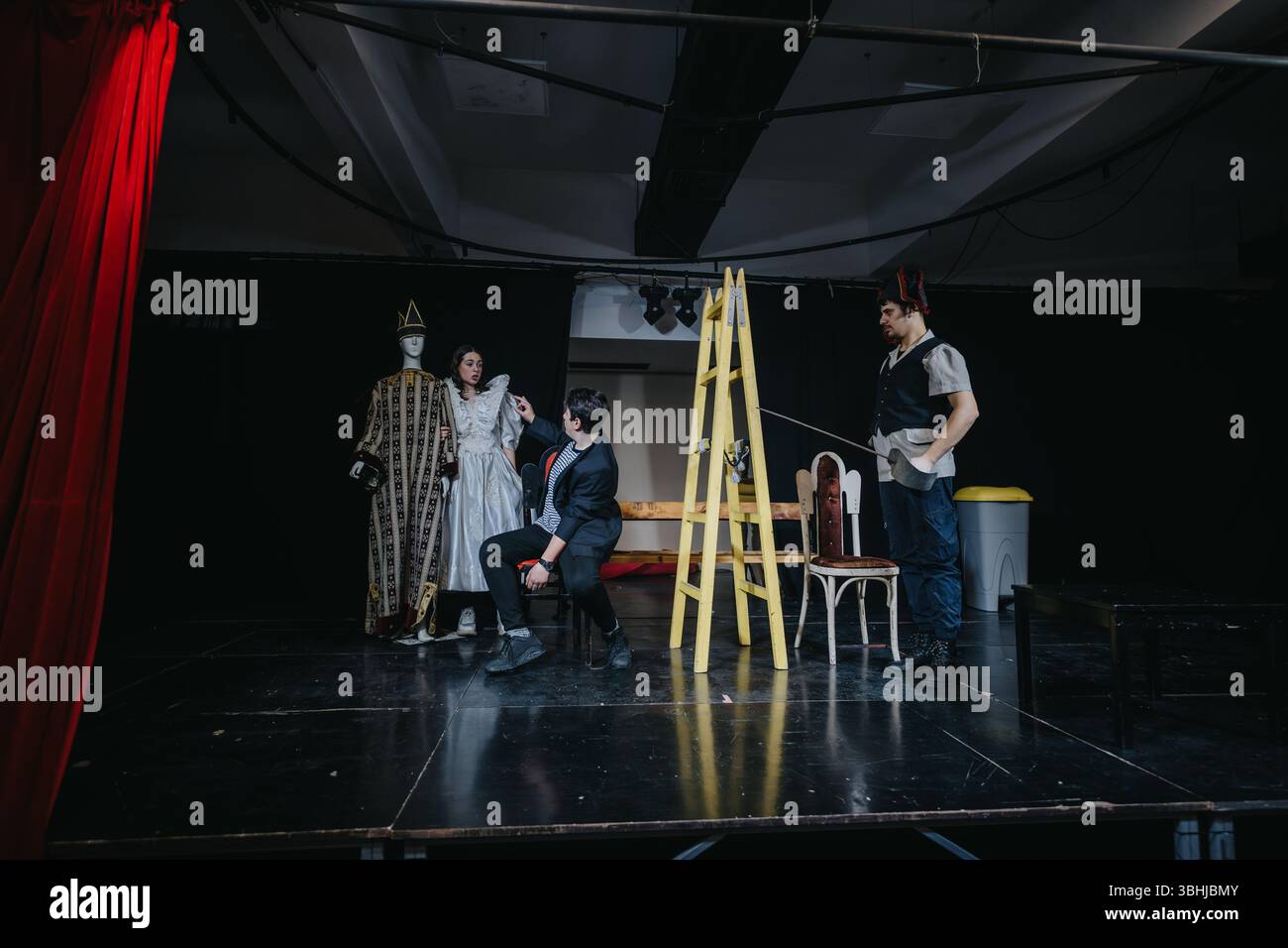 Group of young actors performing a theatrical scene on stage with props ...