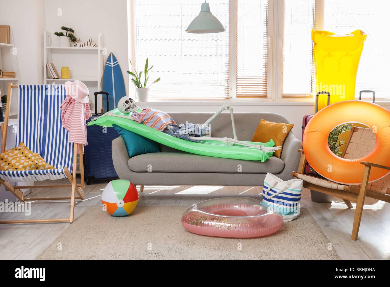 Human skeleton with beach accessories lying on sofa in living room ...