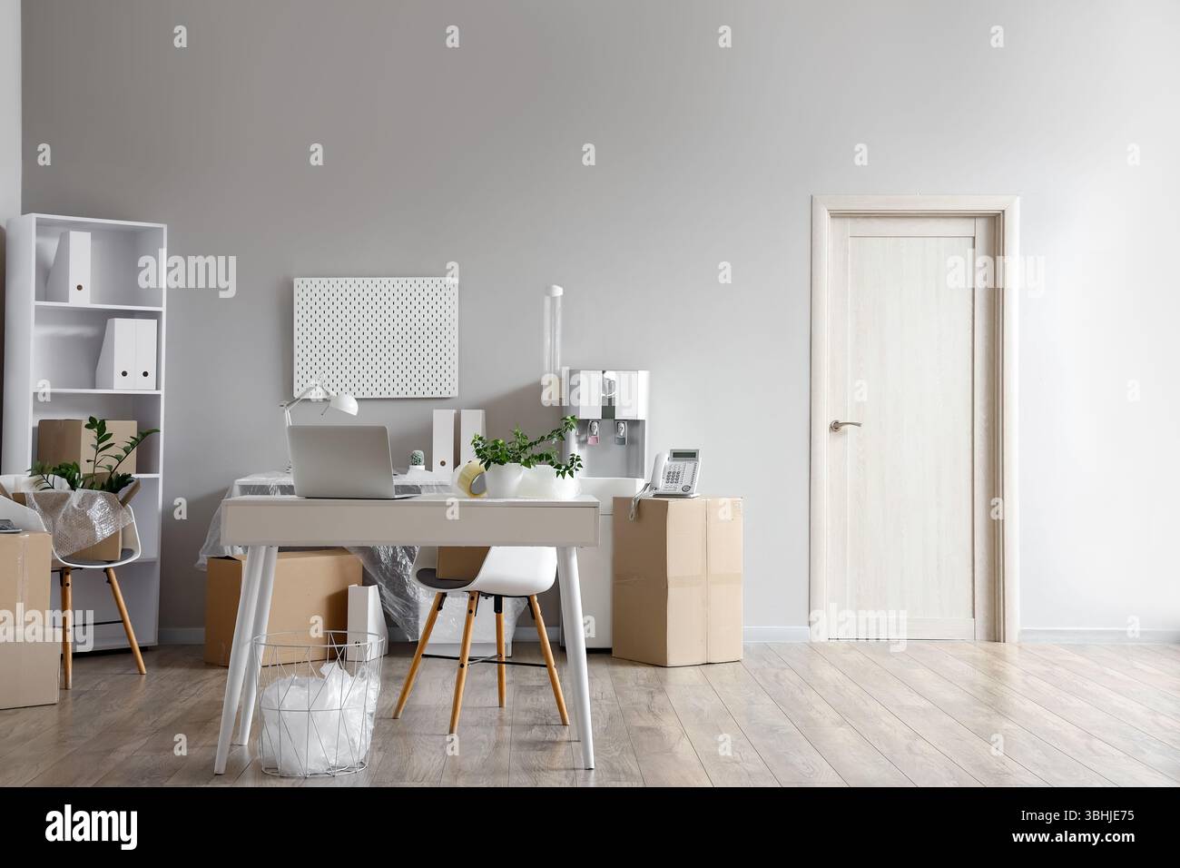 Interior of office with workplace, shelf unit and cardboard boxes on ...