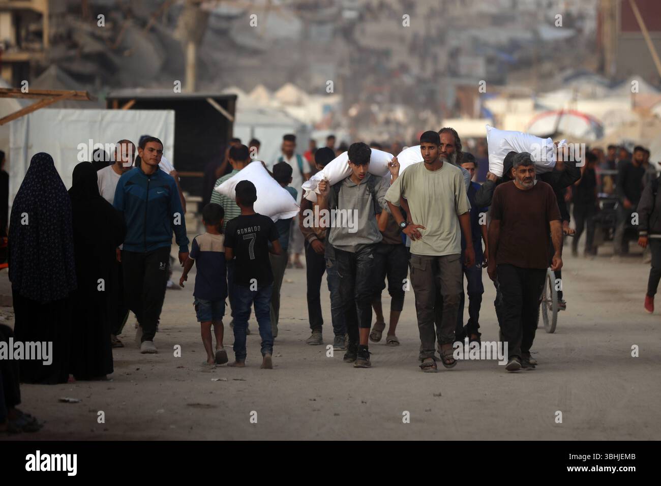 People carry their sacks of flour Flour they got from aid trucks in ...