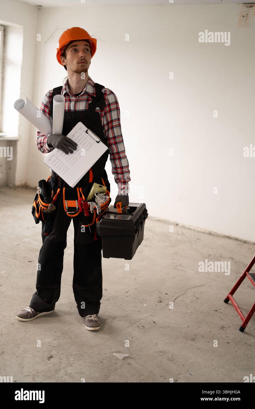 male worker inside flat. Builder in hardhat and work uniform overalls ...