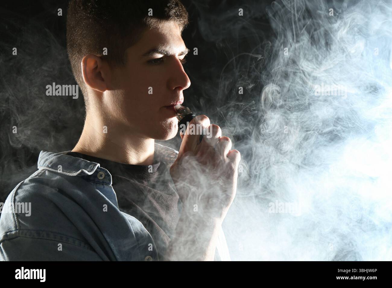 Man using electronic smoking device on black background Stock Photo - Alamy
