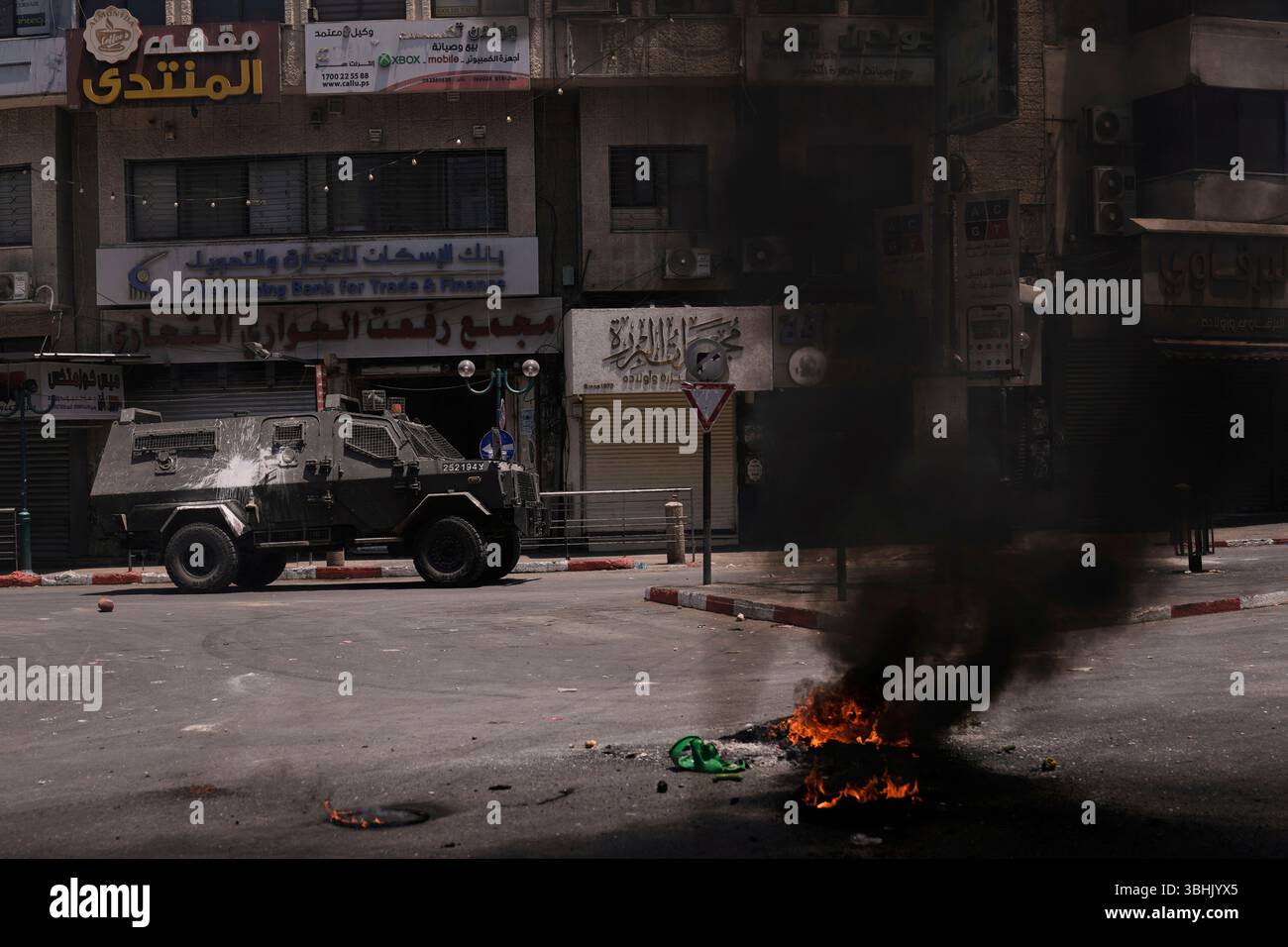 An Israeli armoured vehicle drives near burning tires during a military ...