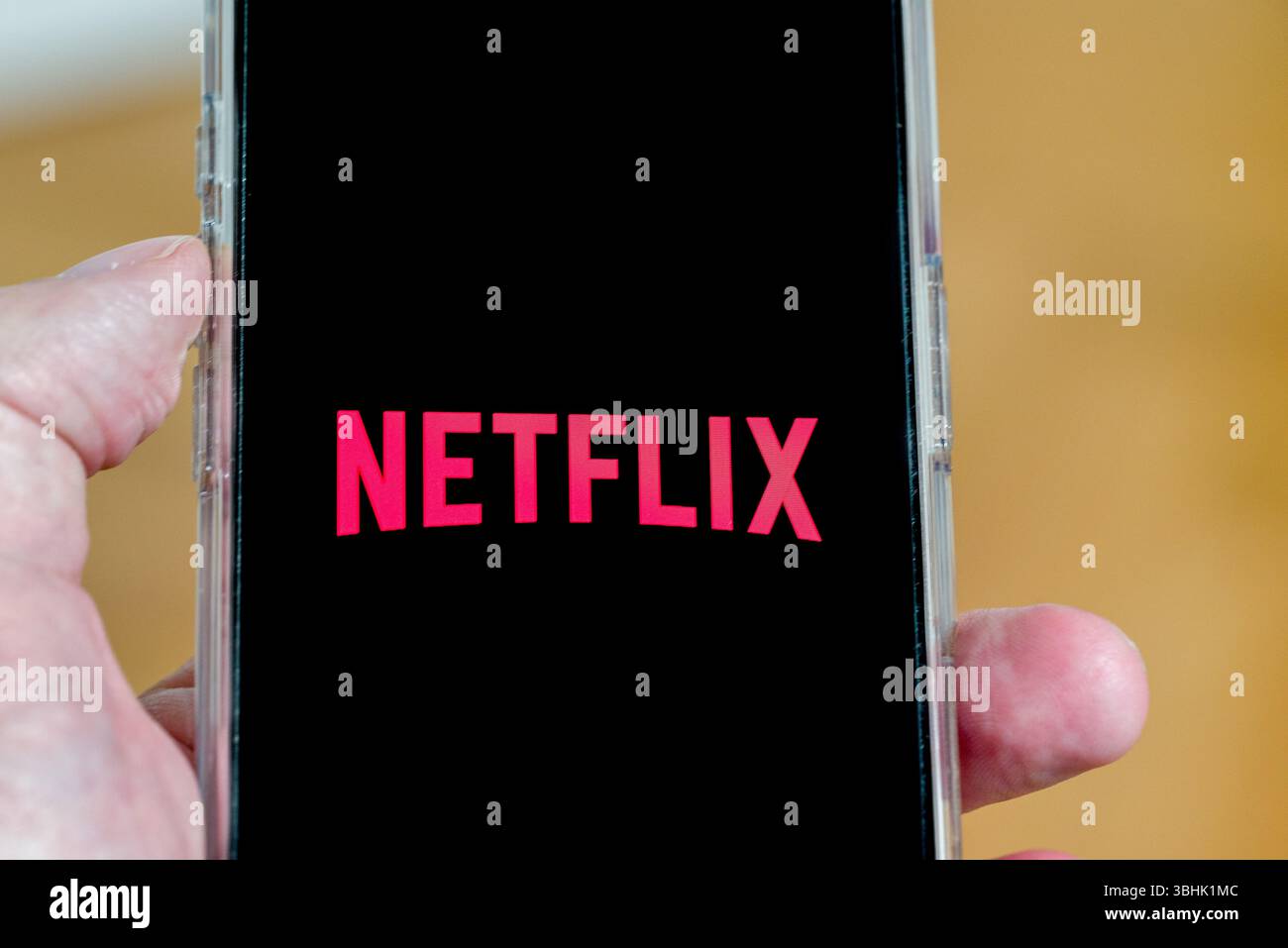 Hand holding smartphone showing netflix logo on screen Stock Photo - Alamy