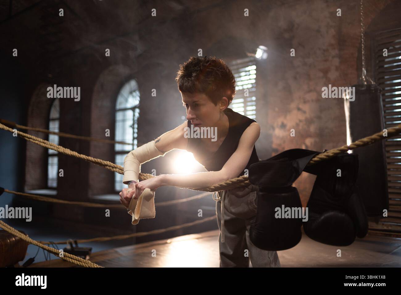 Short-haired athlete pausing in boxing ring, cinematic training break ...