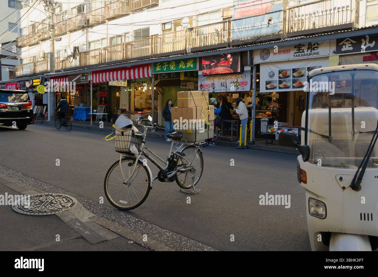 Bicycle loaded with boxes parked across a bustling street lined with ...