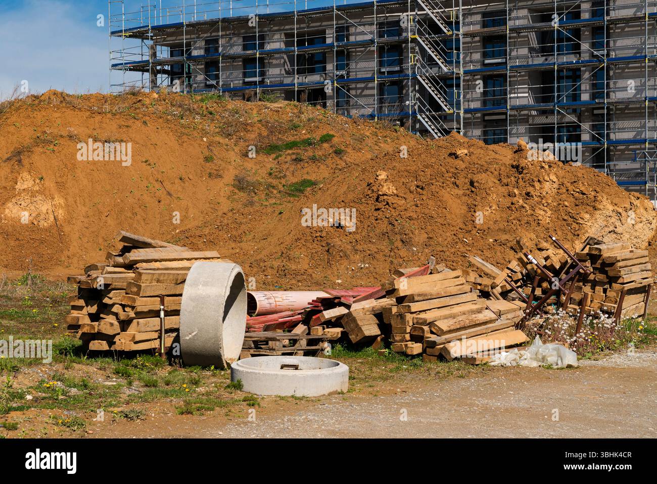 A construction site displays stacks of wooden planks and concrete ...