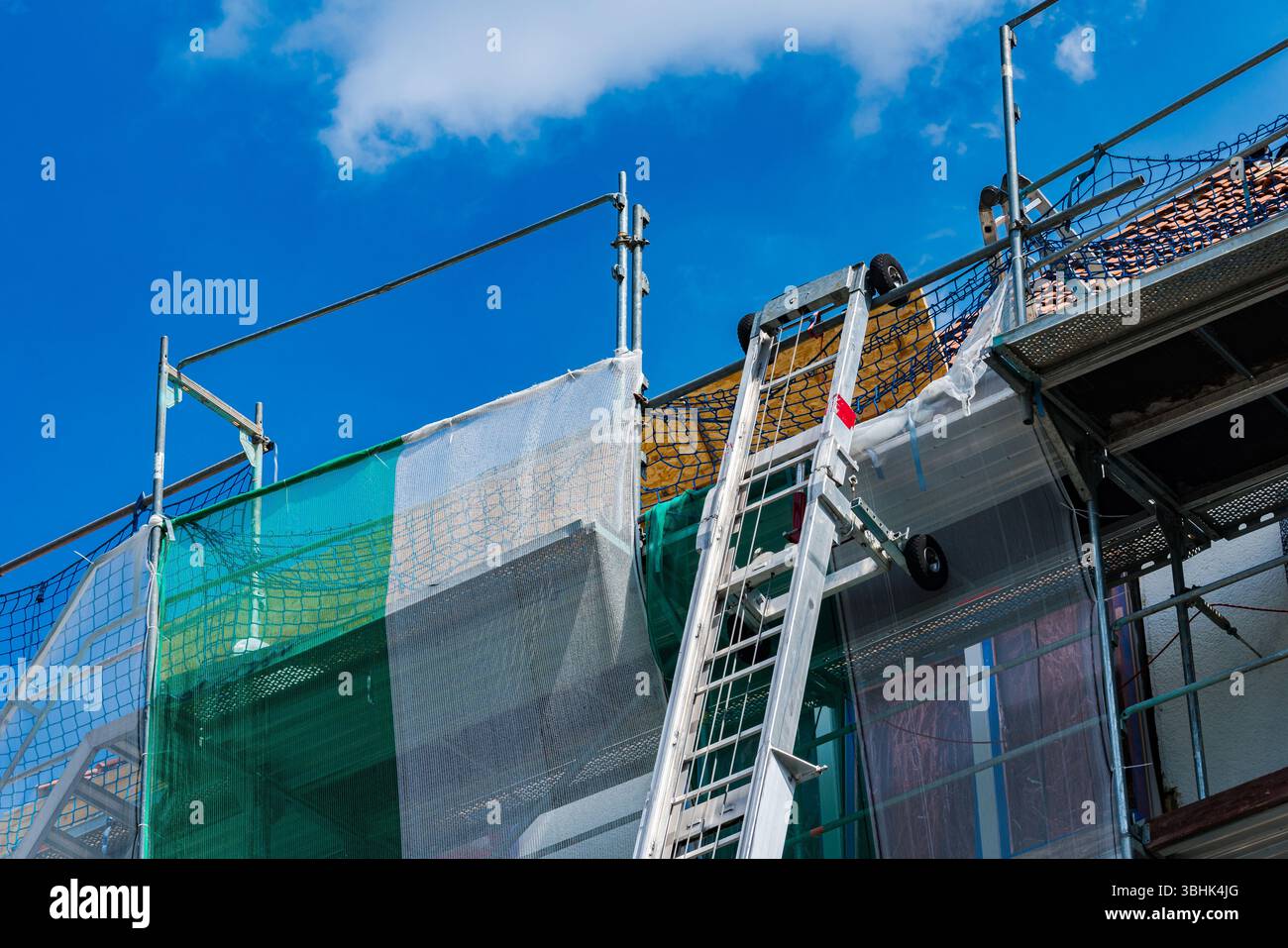 A construction site displays scaffolding secured with safety nets and a ...