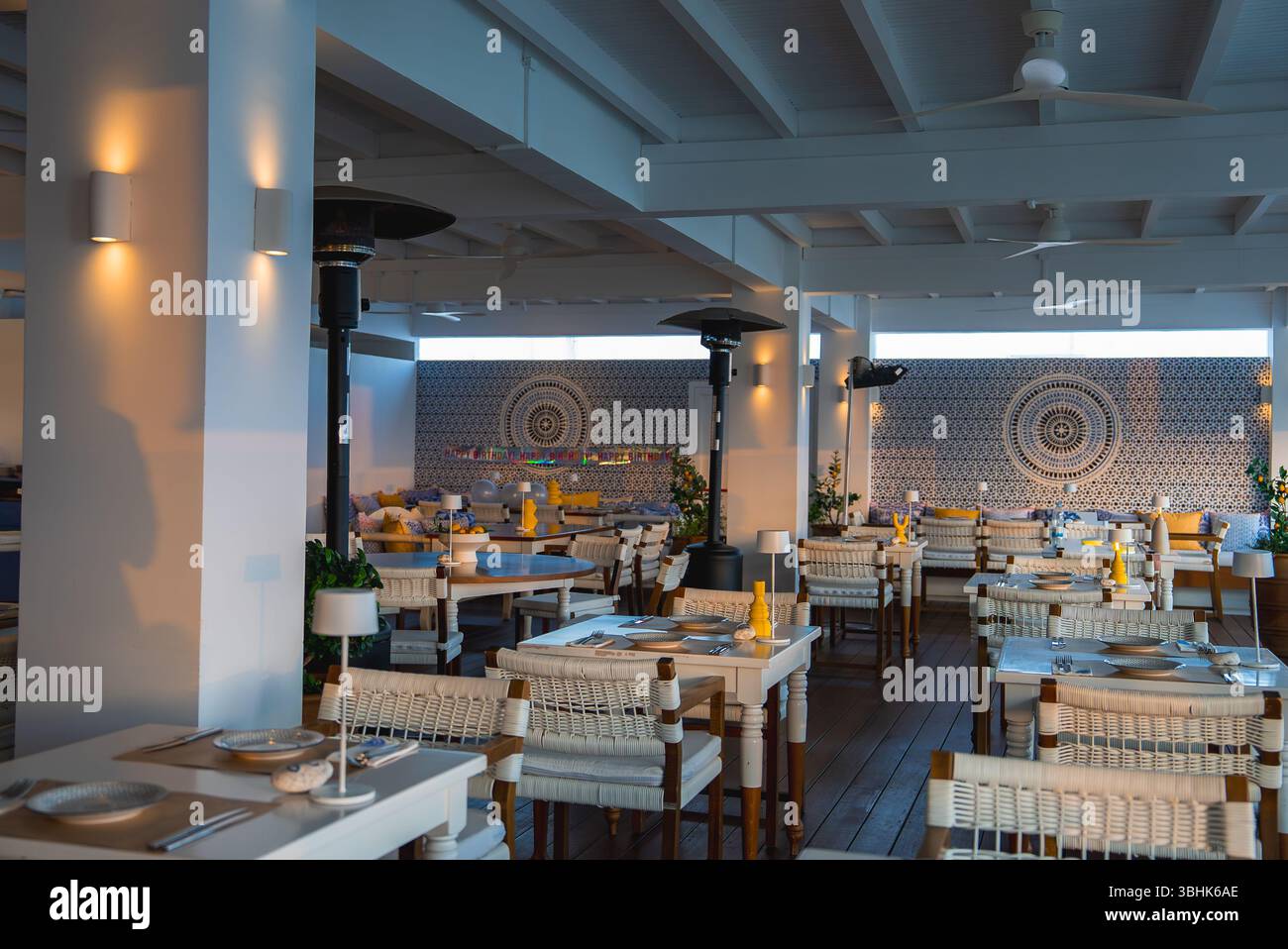 Stylish outdoor dining area with wooden tables, woven chairs ...