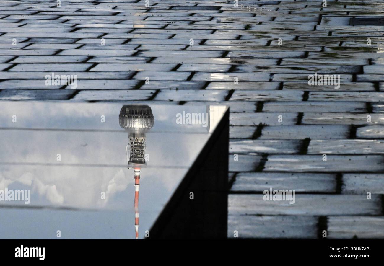 Die Spitze des Fernsehturms spiegelt sich auf einem Steinpodest an der ...