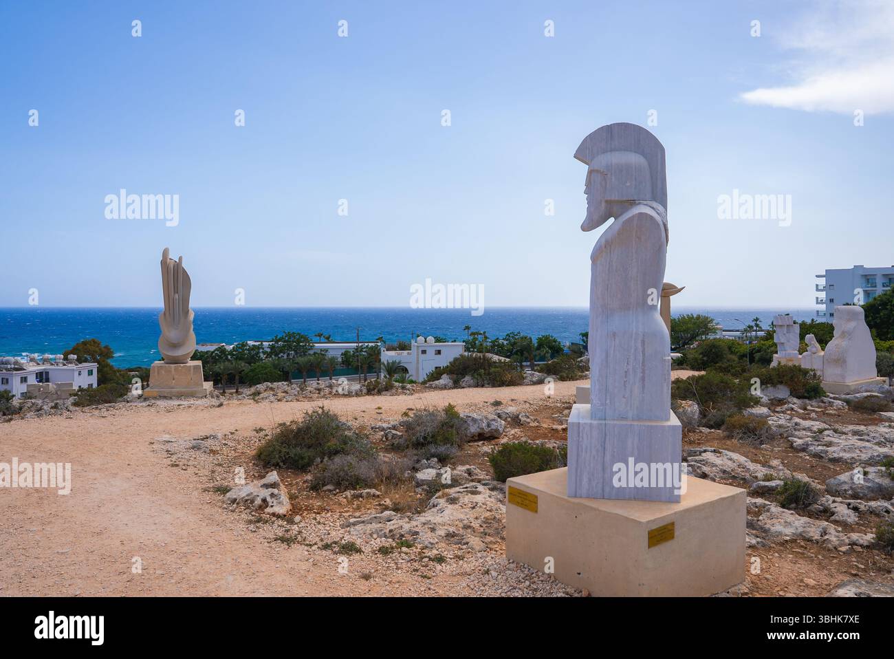 A coastal scene in Cyprus with white marble statues on a rocky hill ...