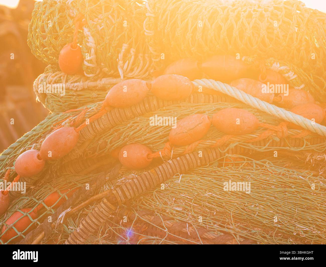 Fishing nets and equipment are stacked at a Sweden harbour, glowing in ...