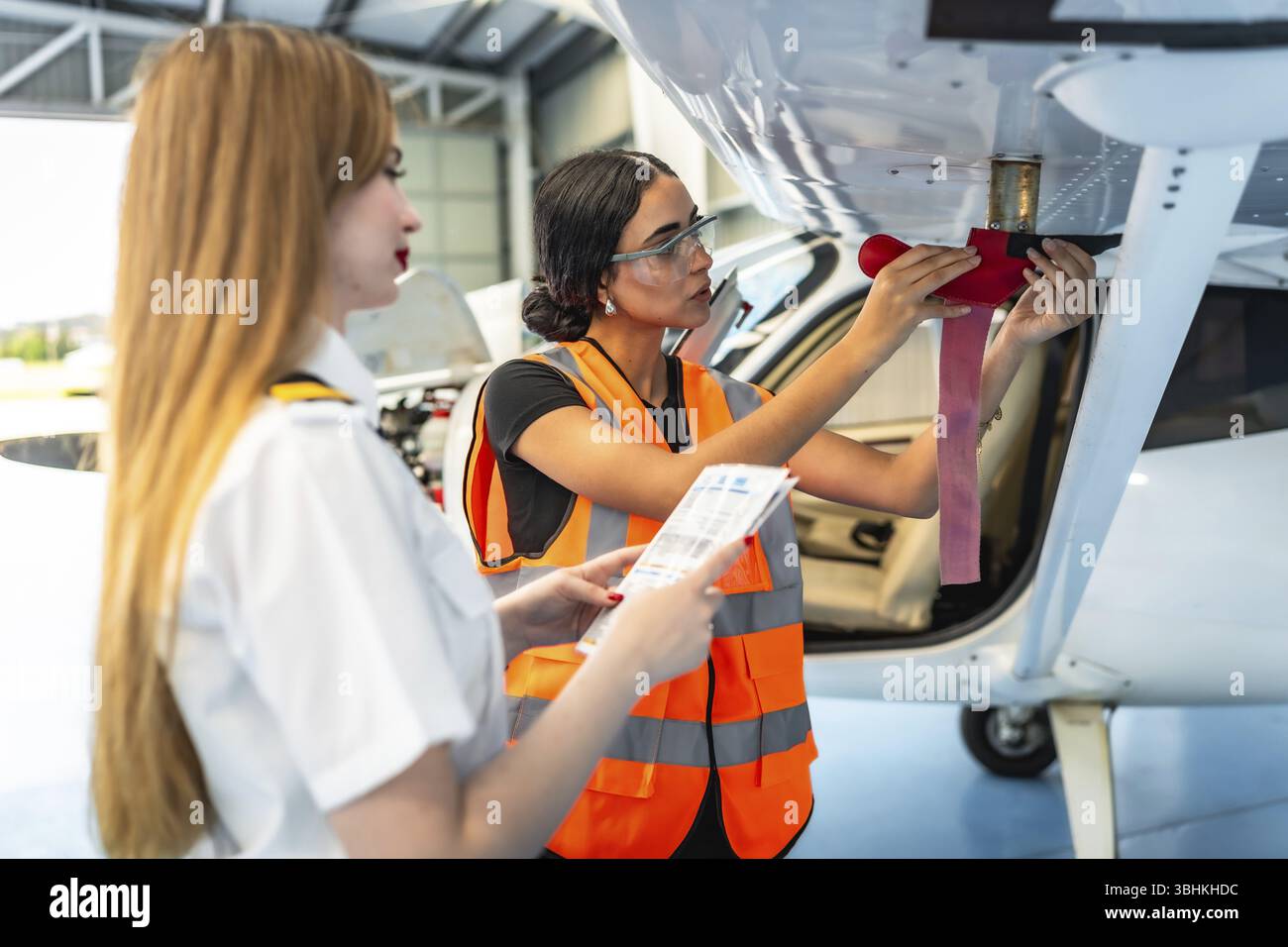 Female aircraft maintenance engineer inspecting airplane wing with ...