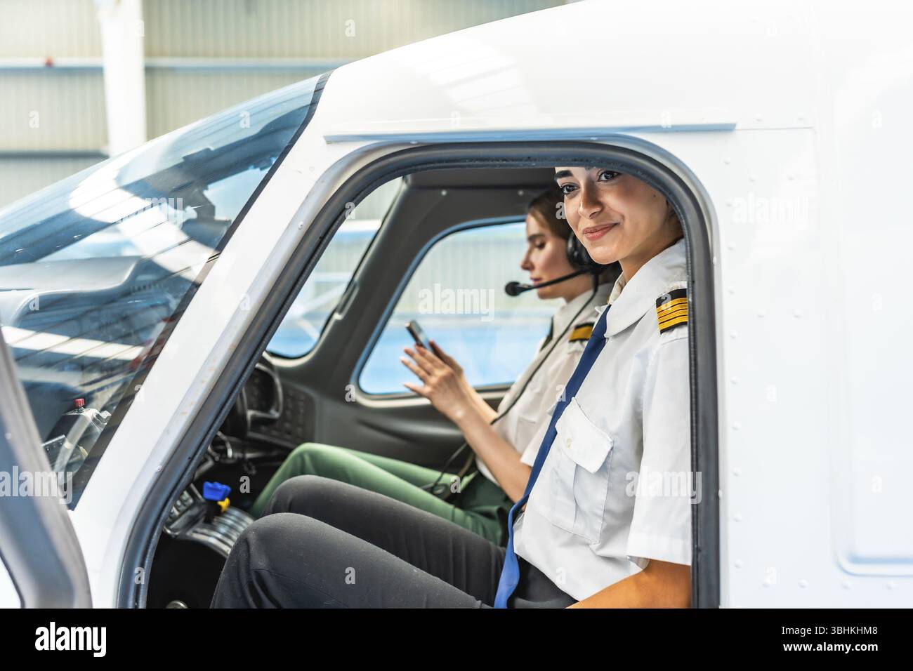 Two female pilots sitting inside the cockpit of a small airplane ...