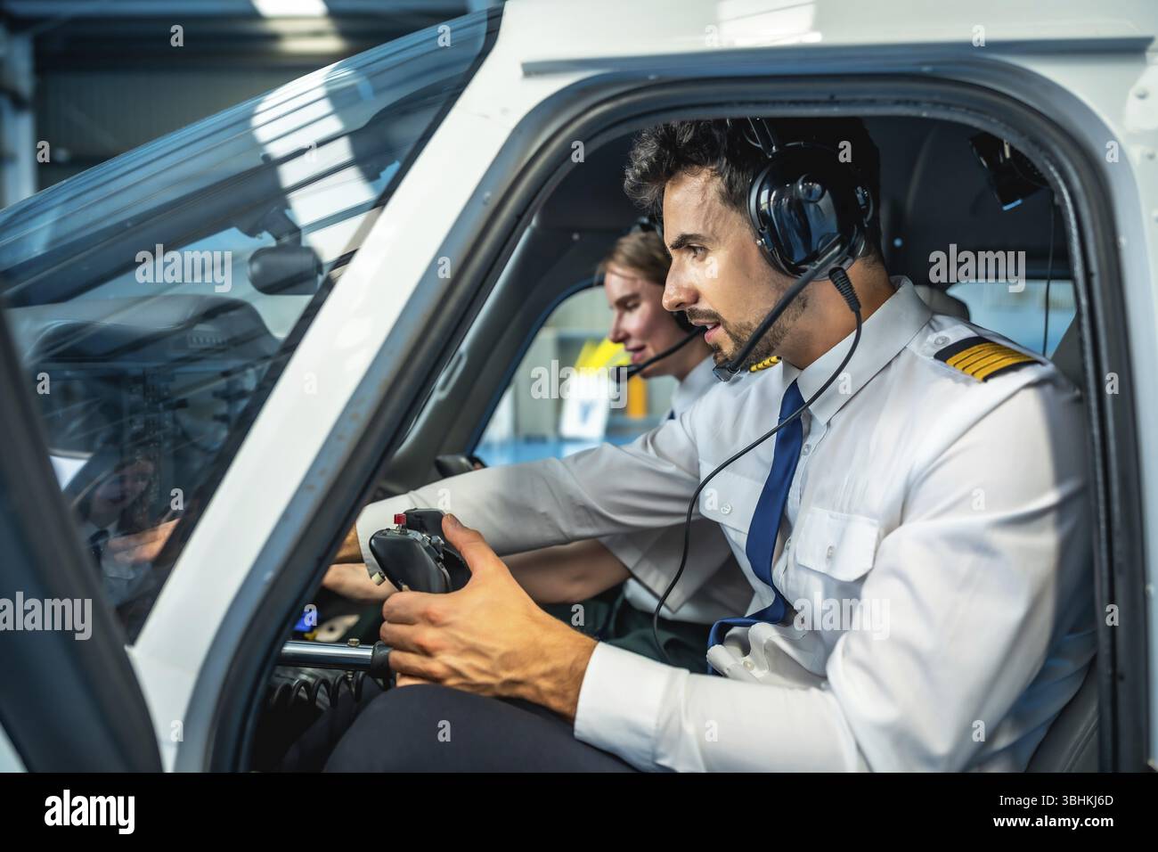 Two male pilots are sitting in the cockpit of a flight simulator, using ...