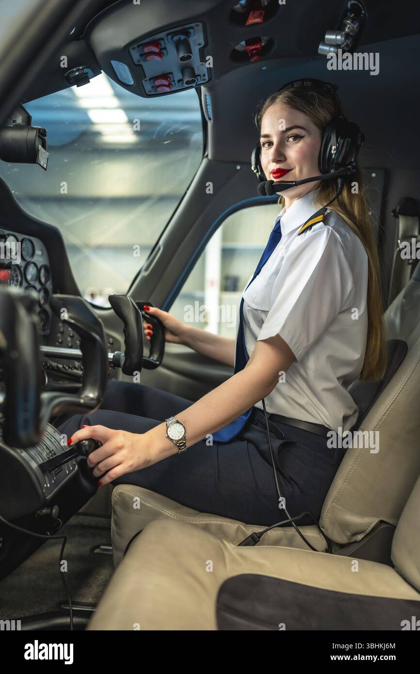 Confident female pilot sitting in the cockpit of a small airplane ...