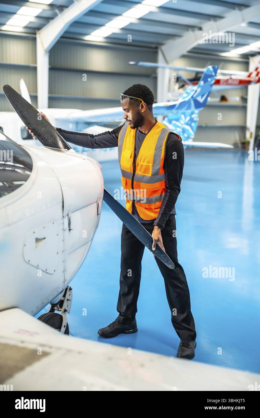 Aircraft maintenance engineer wearing a high visibility vest carefully ...