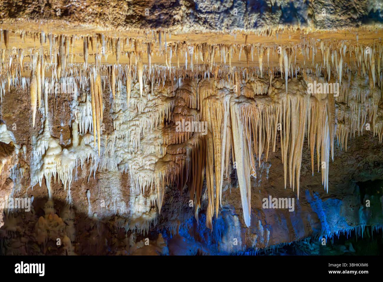 Spectacular golden stalactites and flowstone formations with blue ...