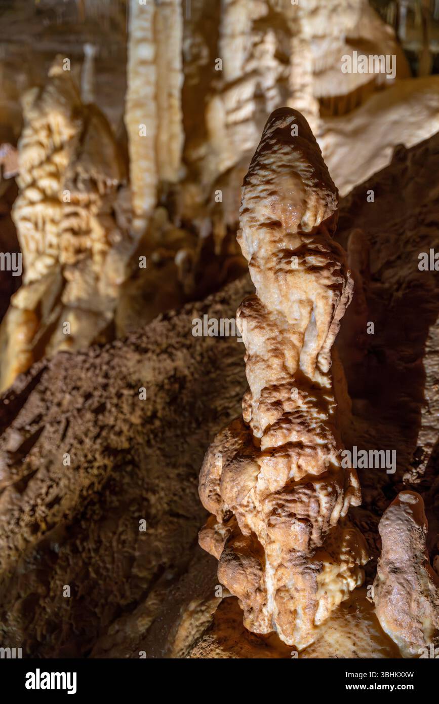 Towering stalagmites and limestone pillars reaching toward cave ceiling ...