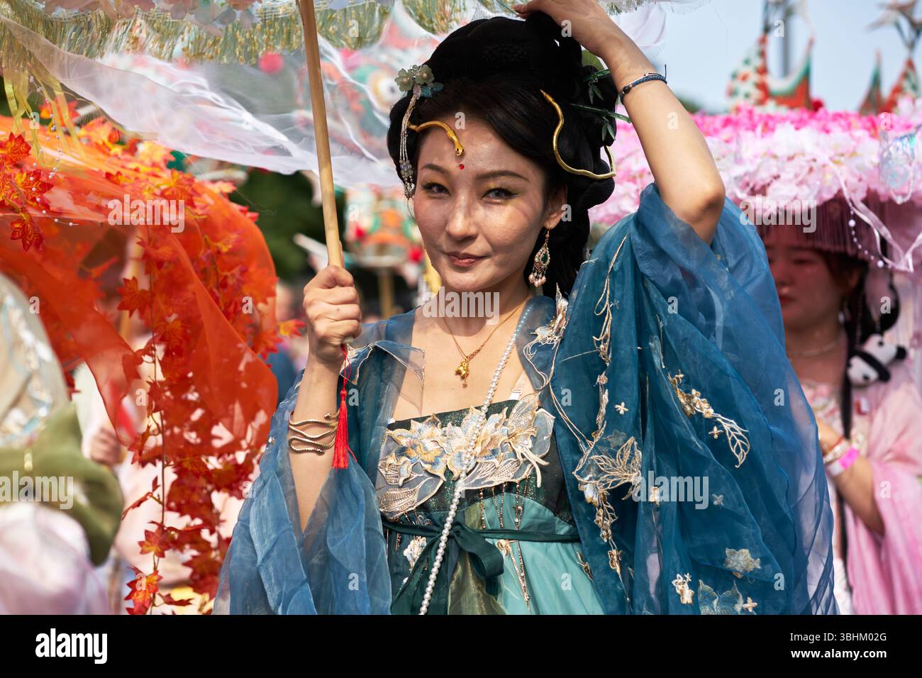 A woman in Chinese traditional costume holds an parasol in year's hand ...