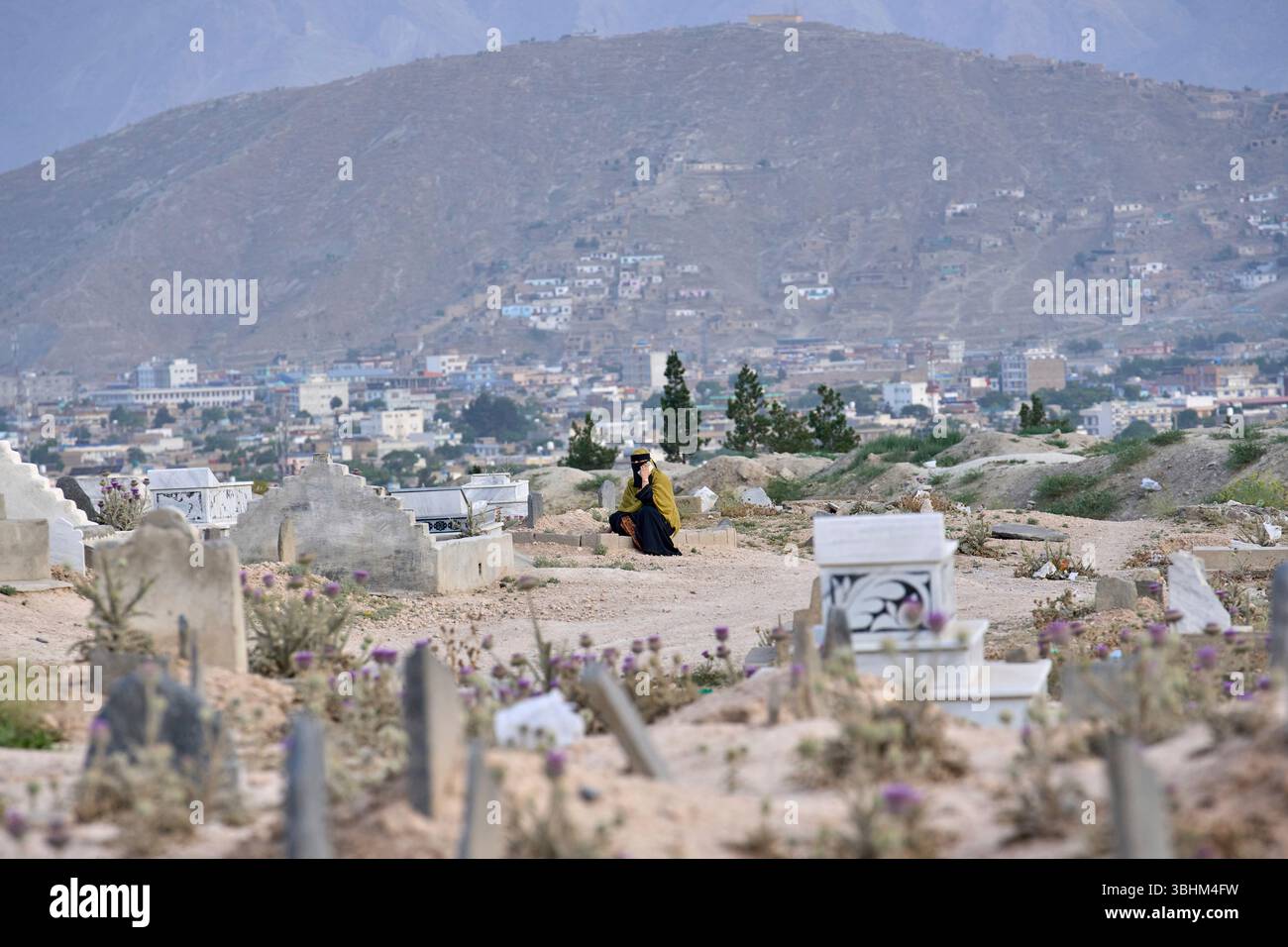 A woman sits on a grave in the cemetery on Nadir Khan hill in Kabul ...