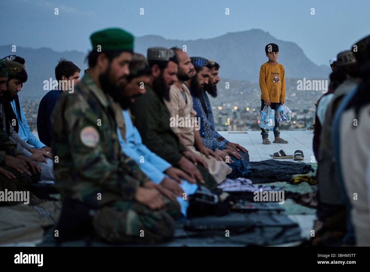 Taliban fighters pray on Nadir Khan hill while a boy watches them, in ...