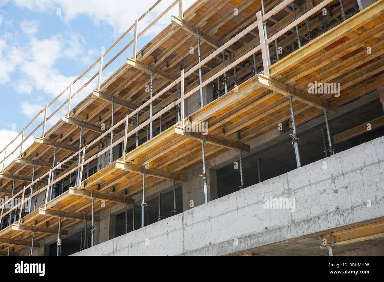 Construction site with scaffolding on concrete building. Wooden planks ...