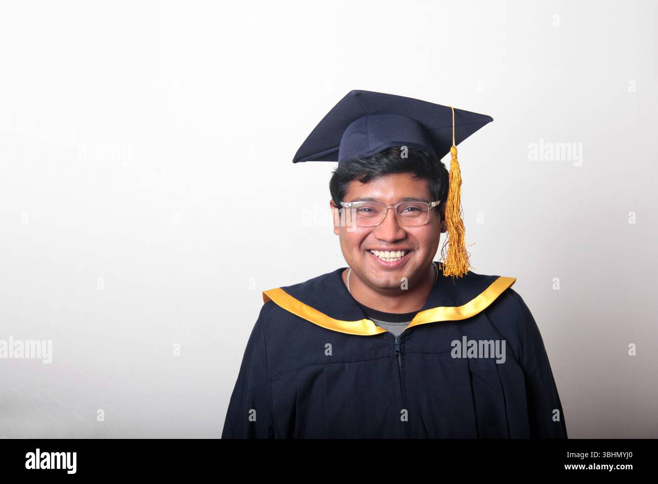 30-year-old dark-skinned Latino man with glasses wears a cap and gown ...
