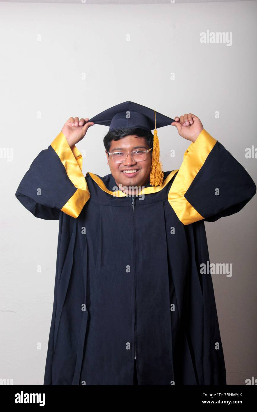 30-year-old dark-skinned Latino man with glasses wears a cap and gown ...