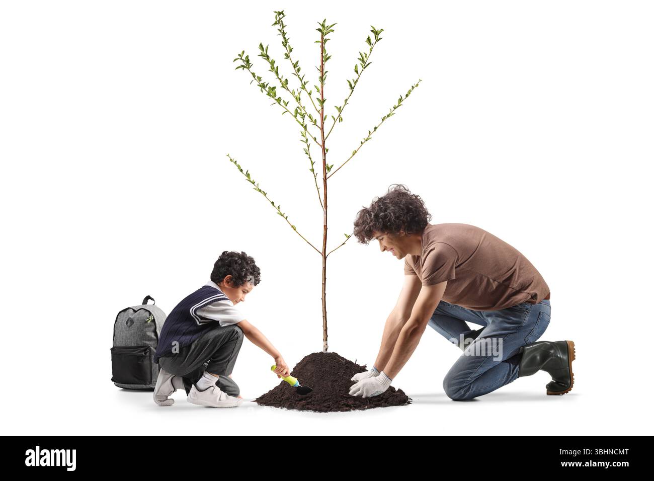 Father and kid digging a pile of earth with a spade and planting a tree ...