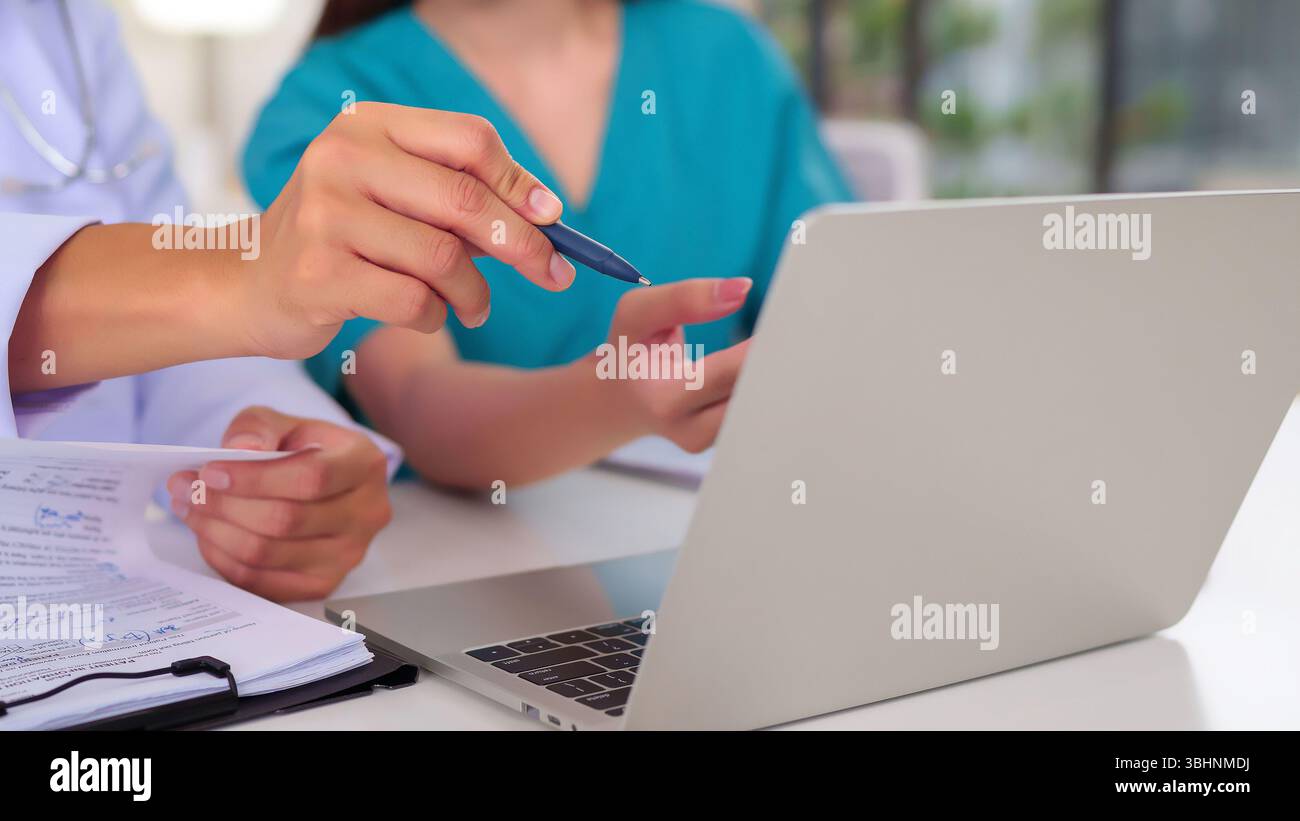Healthcare professionals working on a laptop computer reviewing patient ...