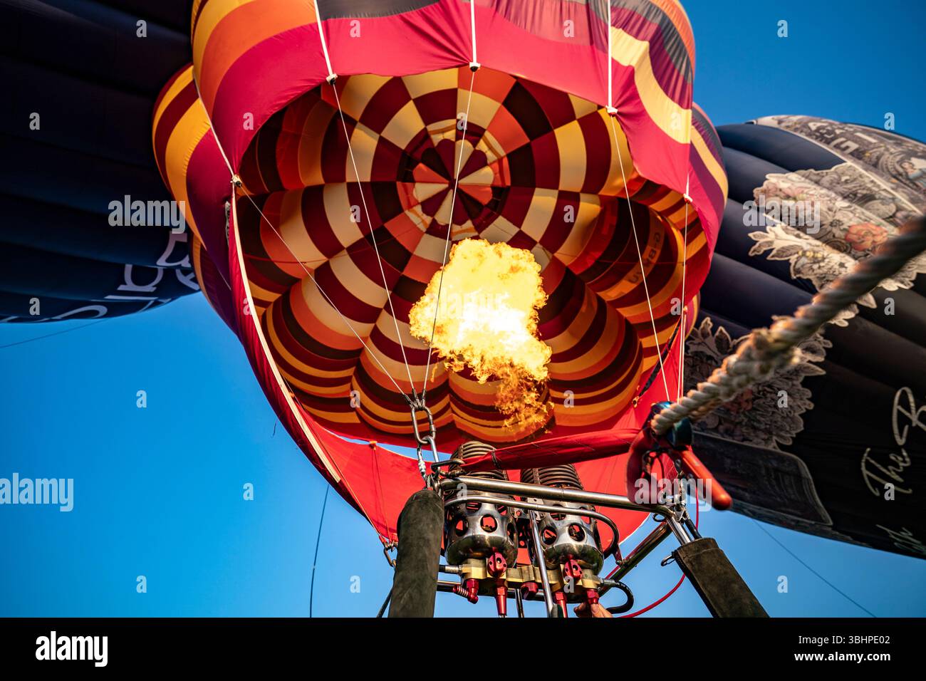 A pilot burns to fill the envelope on a hot air balloon basket as five ...