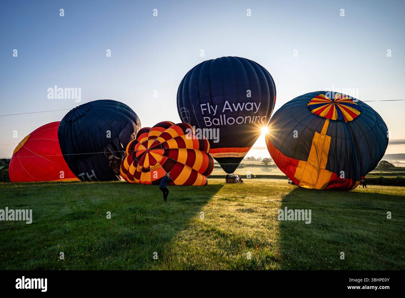 A pilot holds the crown line taut as five hot air balloons prepare for ...