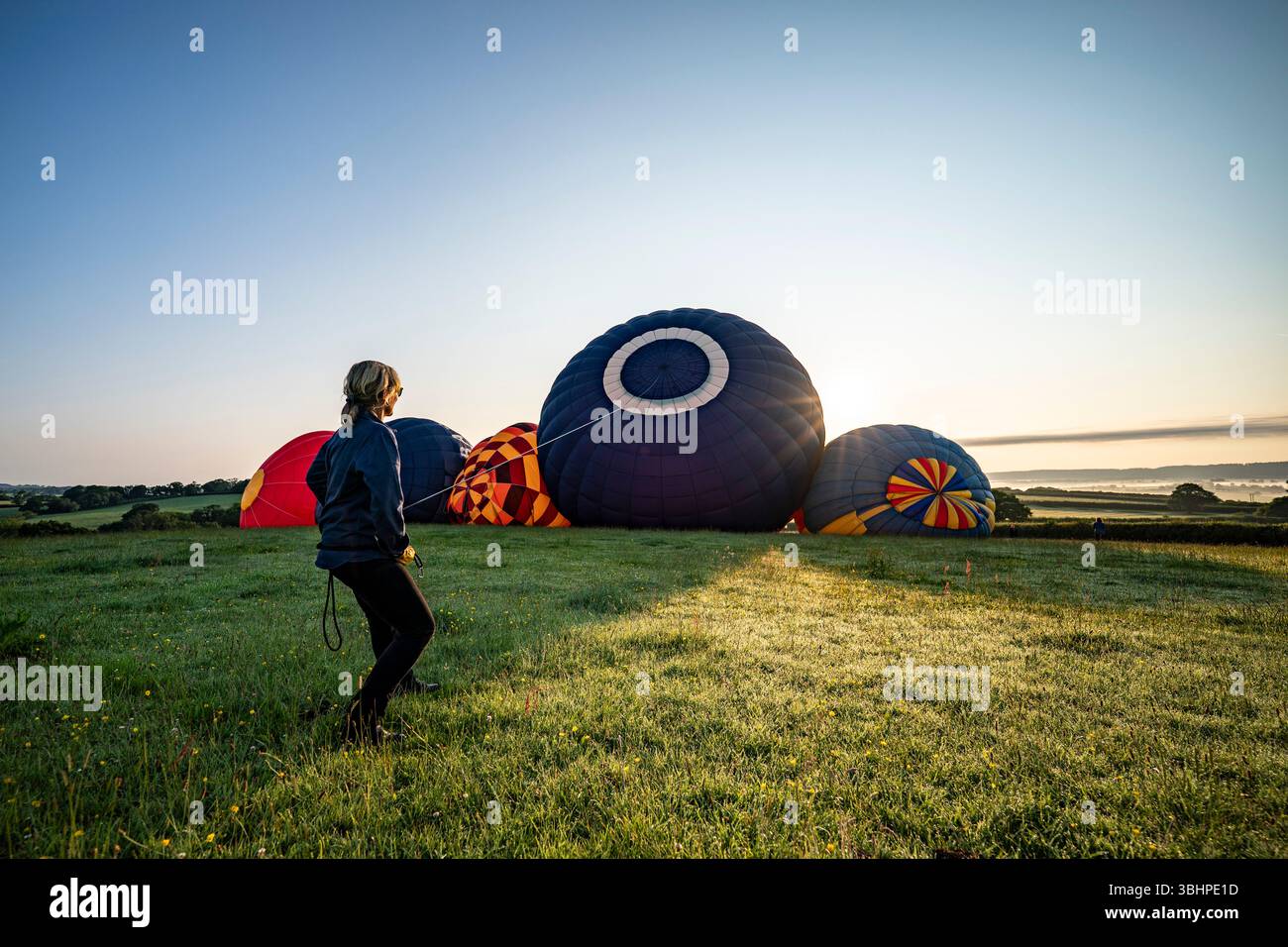A pilot holds the crown line taut as five hot air balloons prepare for ...