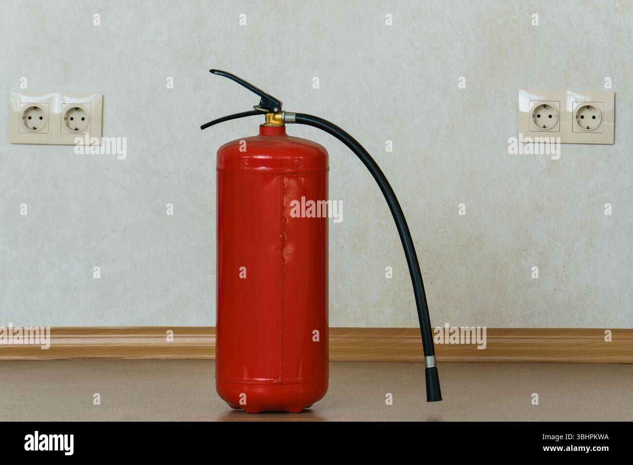 A fire extinguisher with a hose and a socket stands on the floor ...