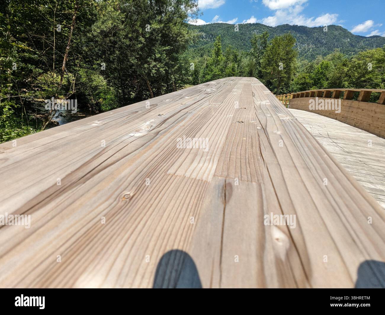 Wooden pedestrian bridge crossing a river in a scenic valley surrounded ...