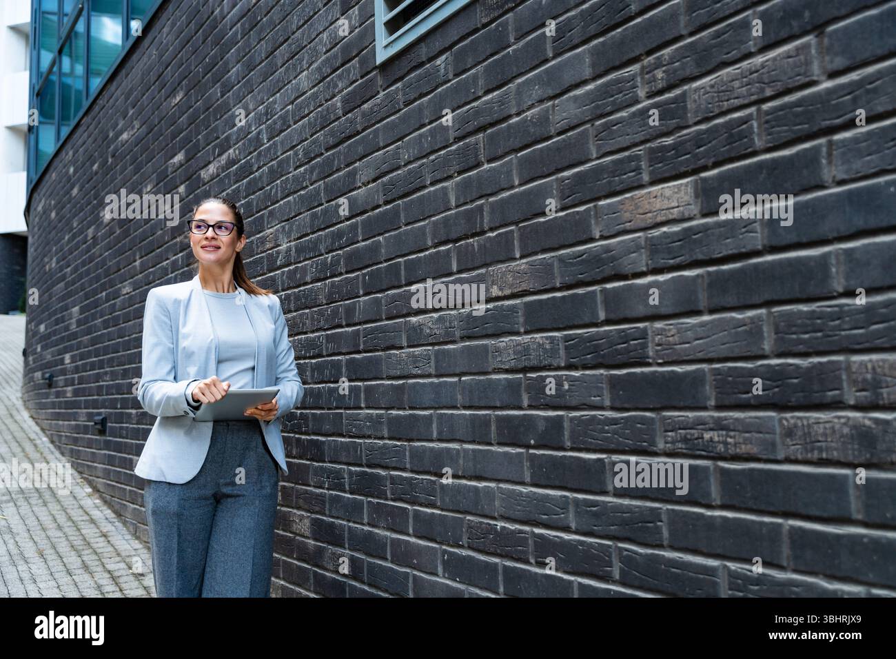 Professional woman standing confidently outside modern office building ...