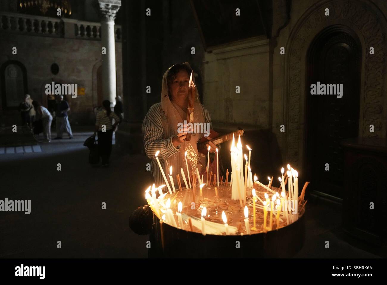 A woman lights candles at the Church of the Holy Sepulcher, the site ...