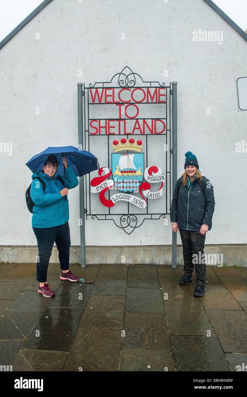 Two women stand under the Welcome to Shetland sign in Lerwick on a ...