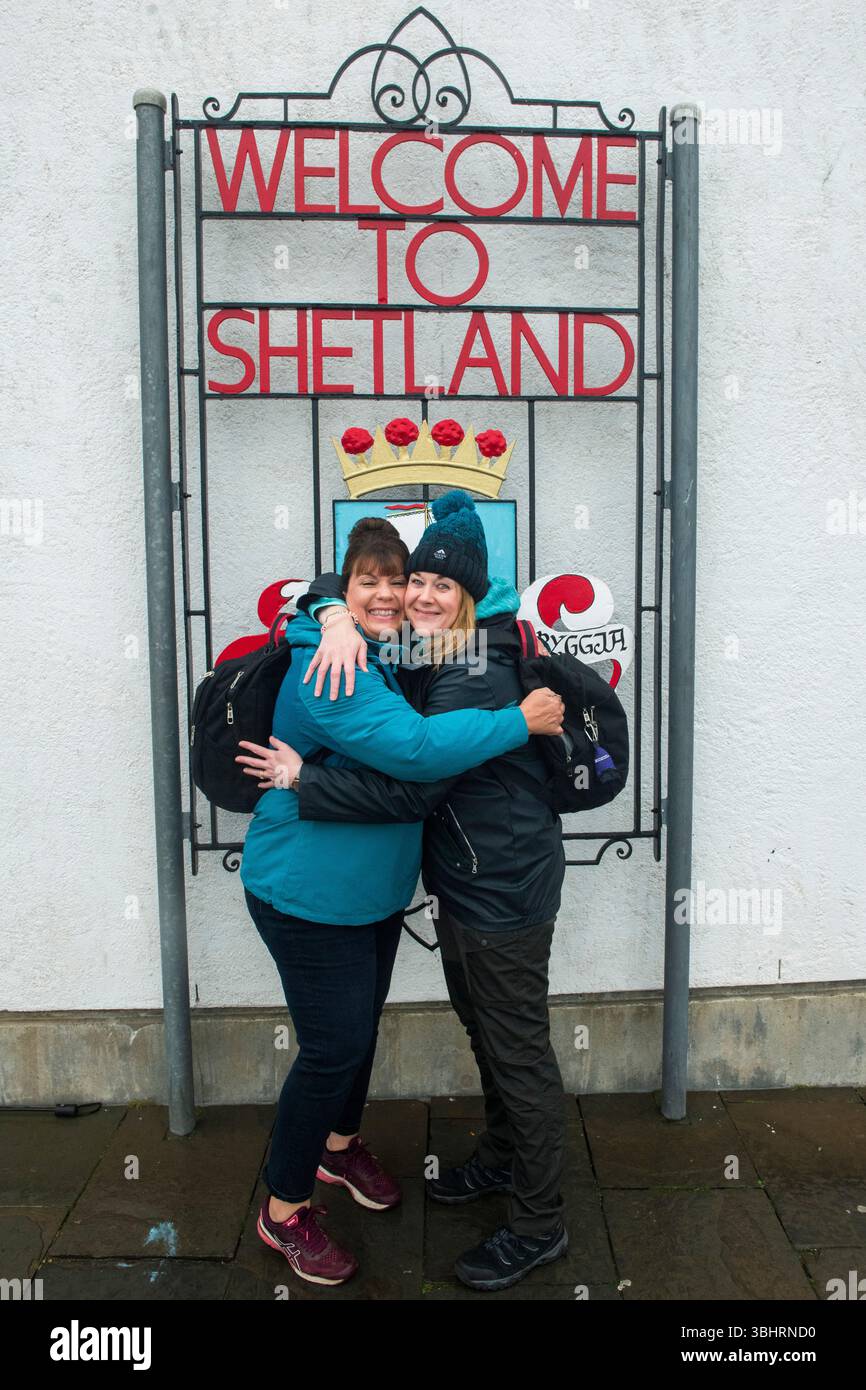 Two women stand under the Welcome to Shetland sign in Lerwick on a ...