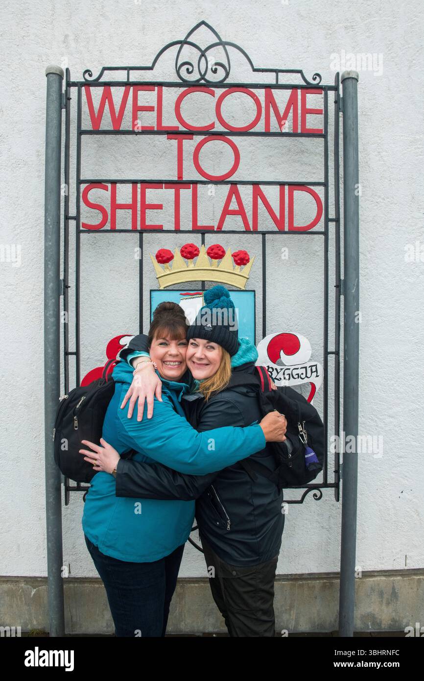 Two women stand under the Welcome to Shetland sign in Lerwick on a ...
