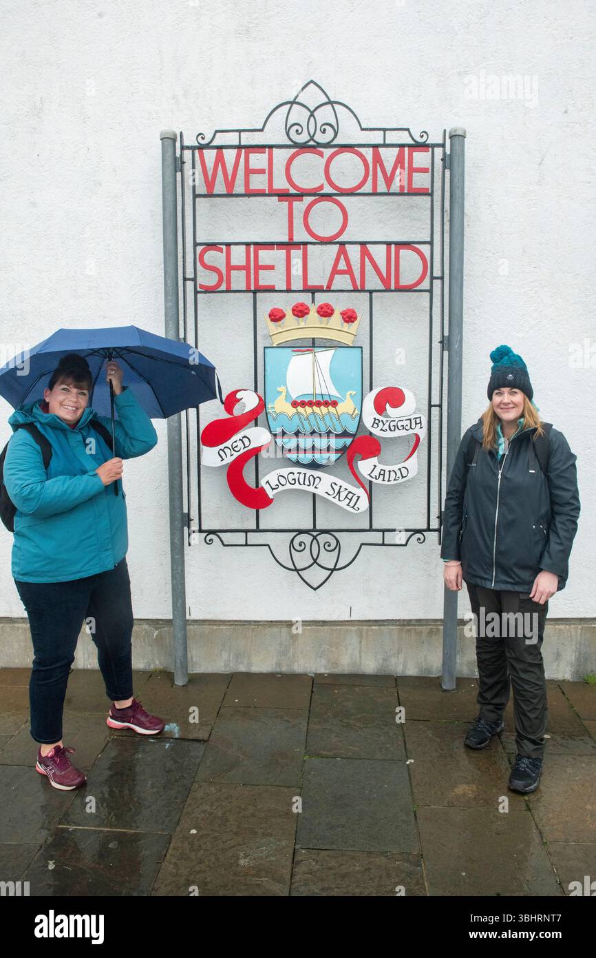 Two women stand under the Welcome to Shetland sign in Lerwick on a ...
